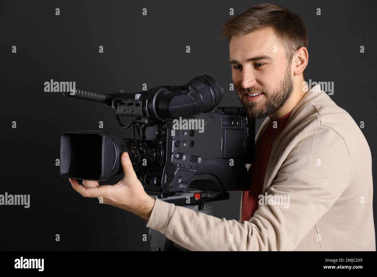 Operator with professional video camera on black background Stock Photo ...
