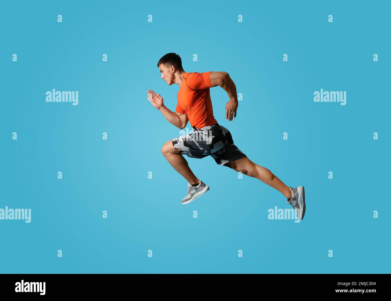 Athletic young man running on light blue background, side view Stock ...