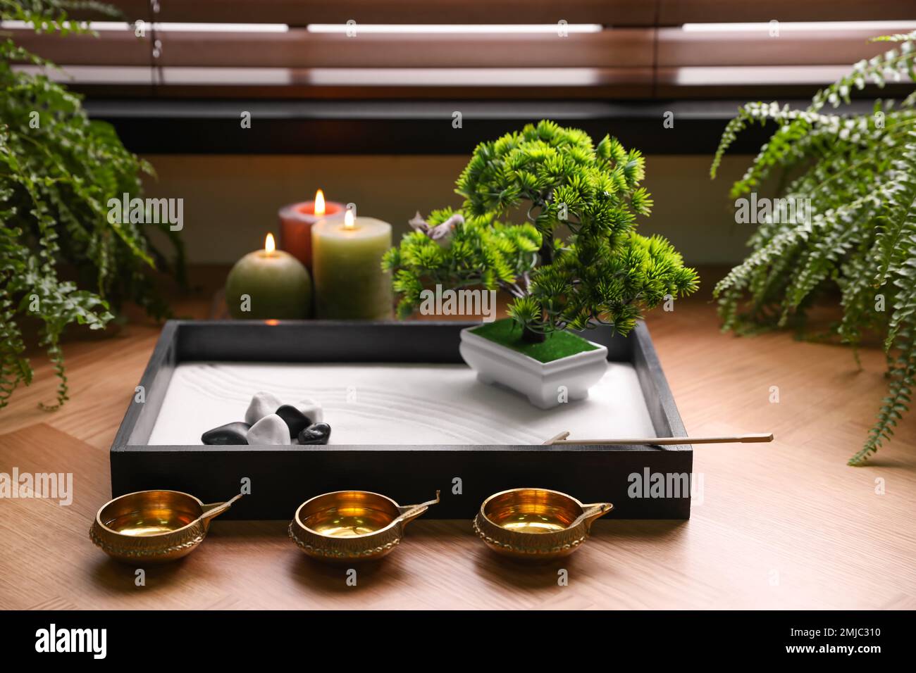 Beautiful miniature zen garden, candles and oil lamps near window ...