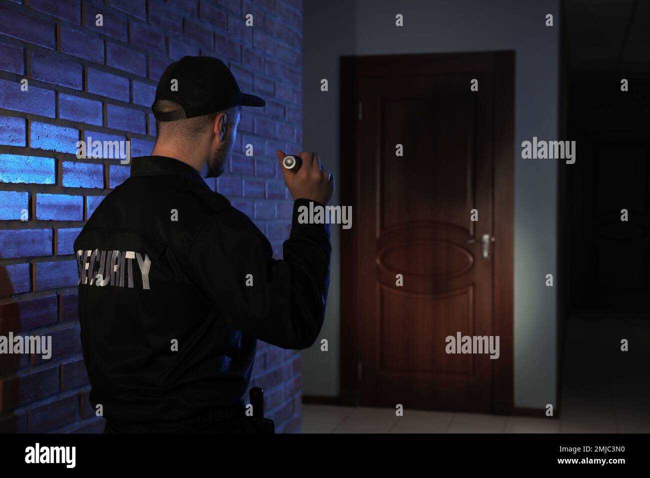 Male security guard with flashlight in dark corridor Stock Photo - Alamy