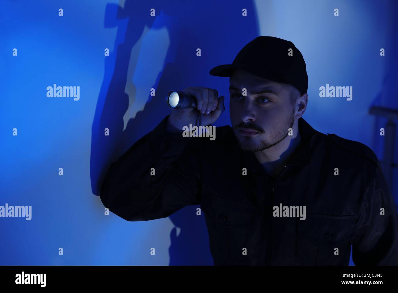 Male security guard with flashlight in dark room Stock Photo - Alamy