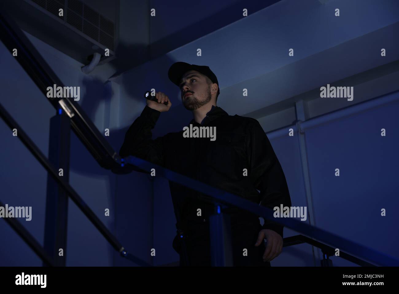 Male security guard with flashlight on stairs in darkness Stock Photo ...