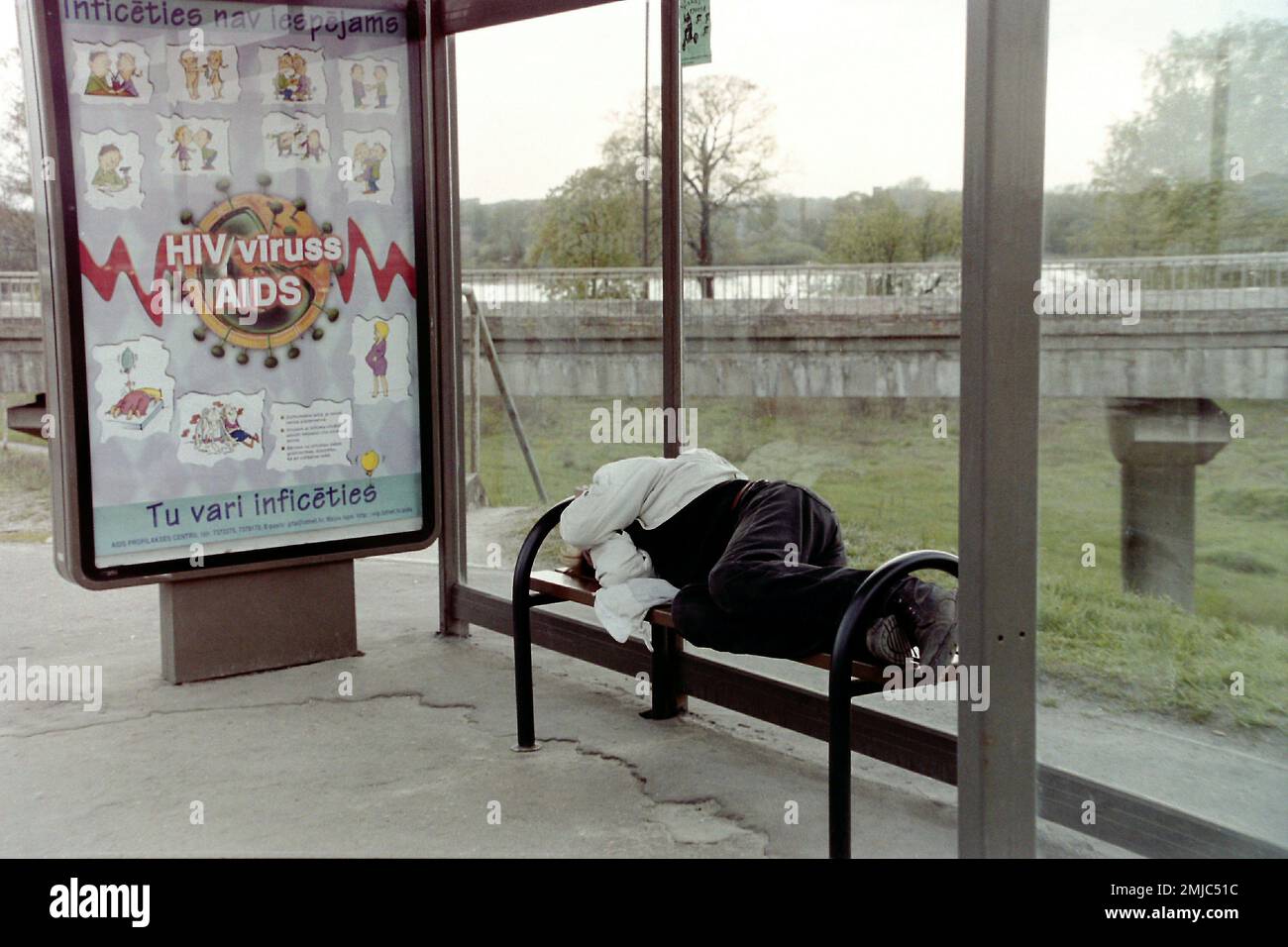 A sleeping man on a bench at a public transport stop in Riga. The ...
