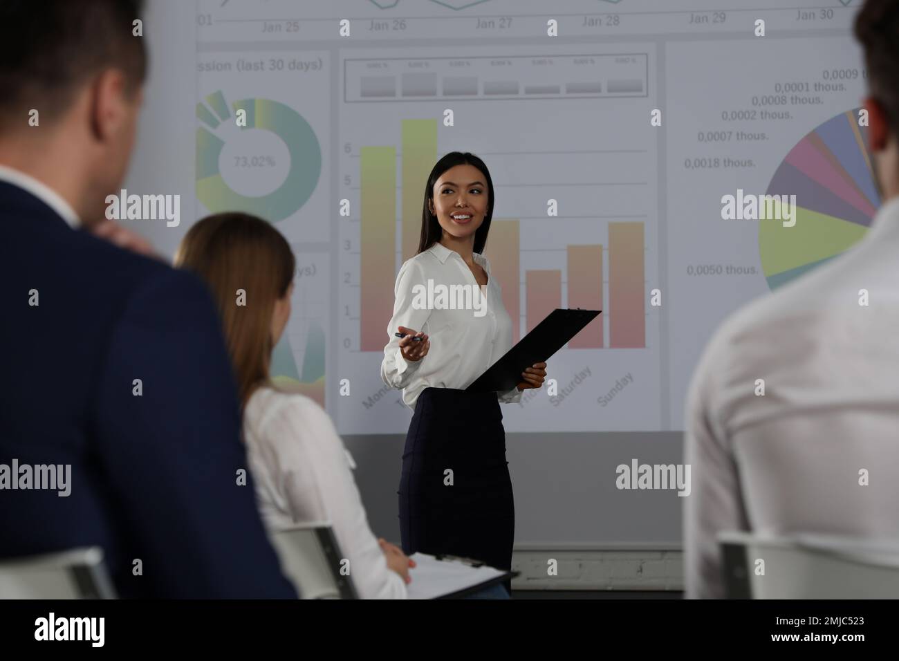 Female business trainer giving lecture in conference room with ...