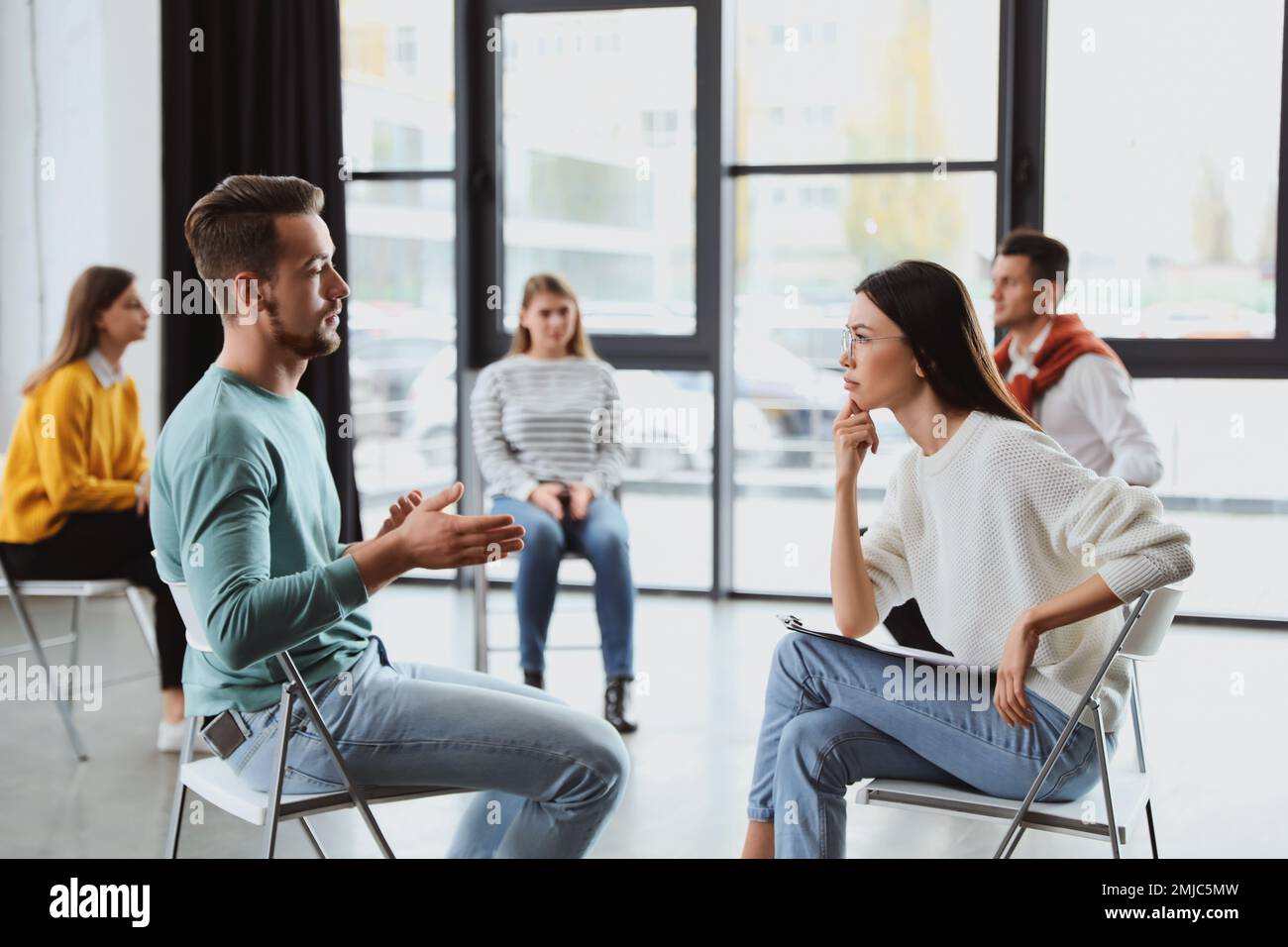 Psychotherapist working with patient in group therapy session indoors ...