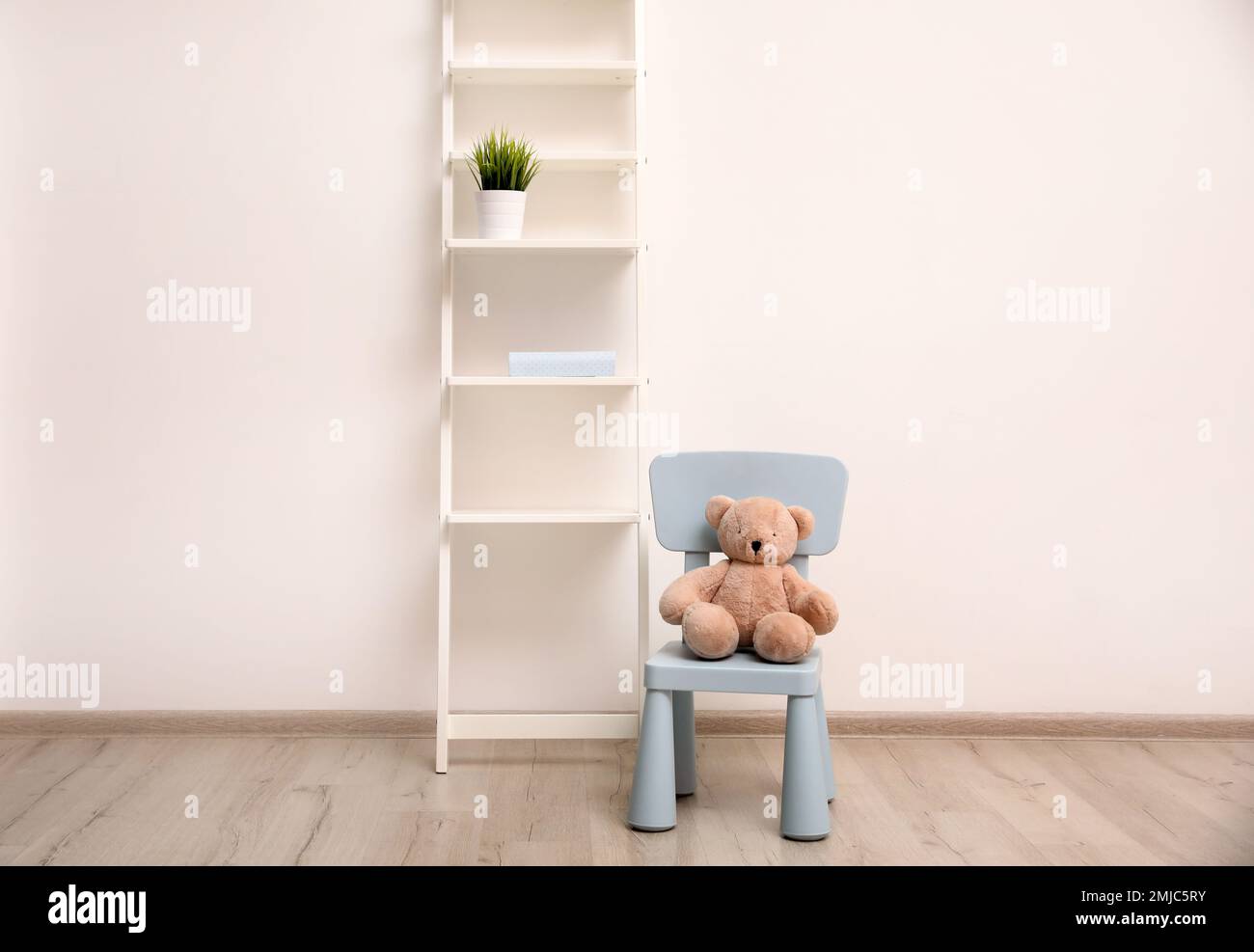 Teddy bear on chair and shelving unit near wall in child room Stock ...