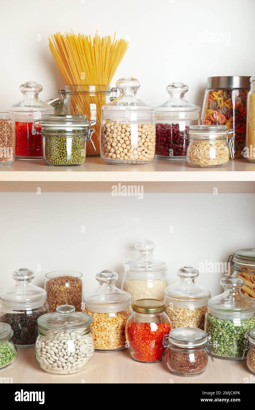 Glass jars with different types of groats and pasta on wooden shelves ...