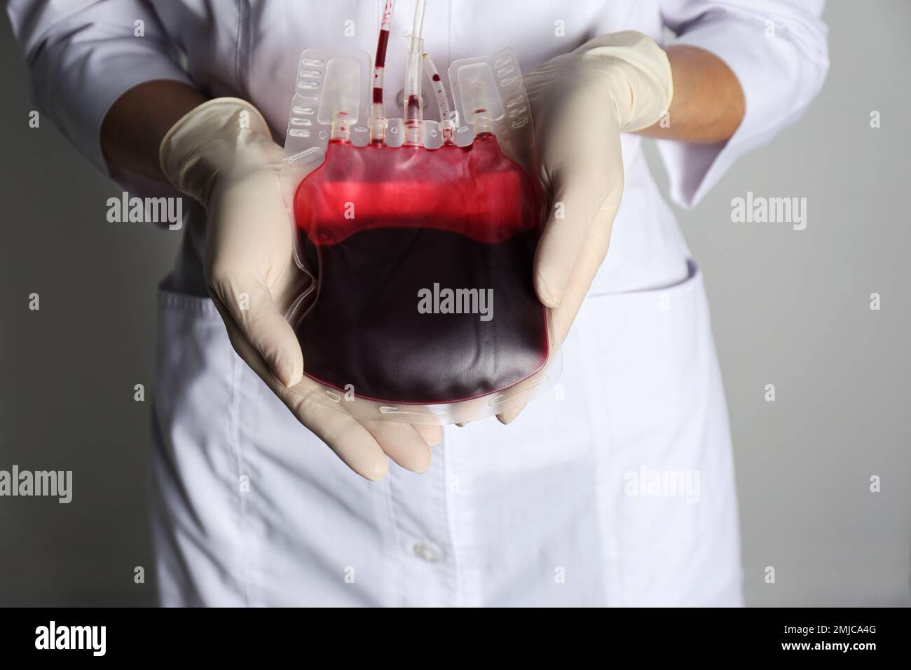 Woman holding blood for transfusion on light grey background, closeup ...