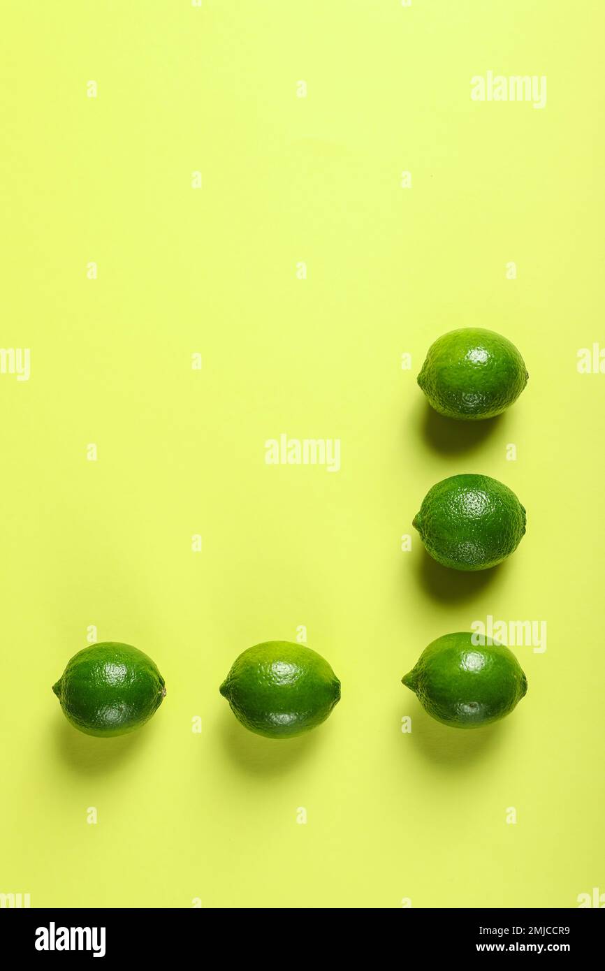 Flat lay composition with fresh juicy limes on yellow background, space ...