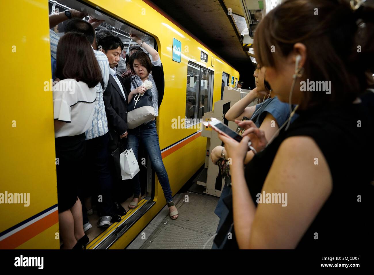Commuters try to squeeze themselves into an overcrowded train during ...