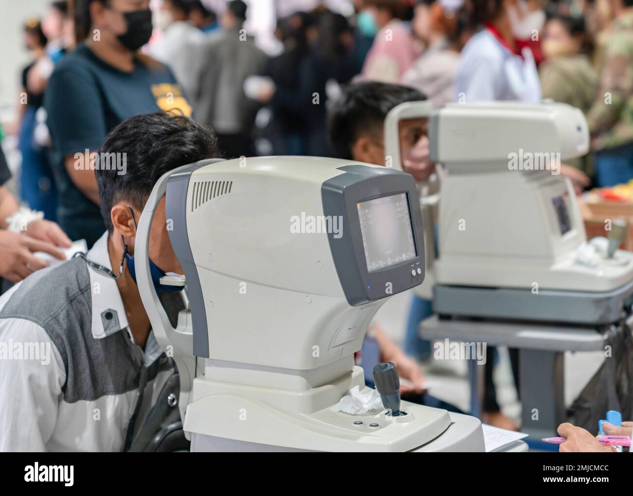Optician examining man's eyes with a machine in annual health check Stock Photo - Alamy