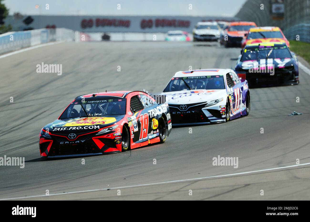 Martin Truex, Jr., and Denny Hamlin head into Turn 1 during a NASCAR ...