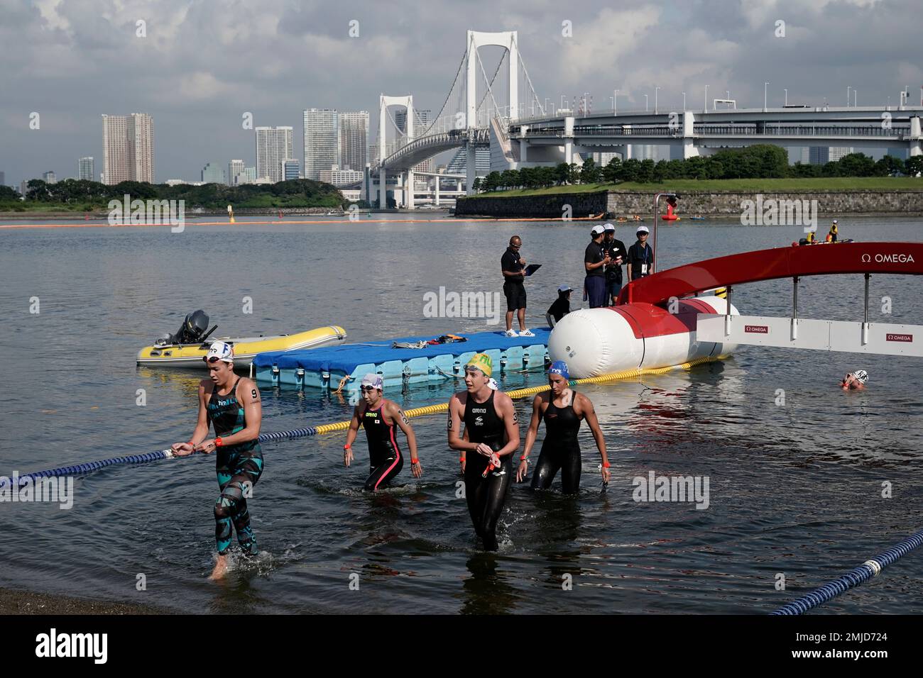 Athletes walk out of the water after competing in a marathon swimming ...
