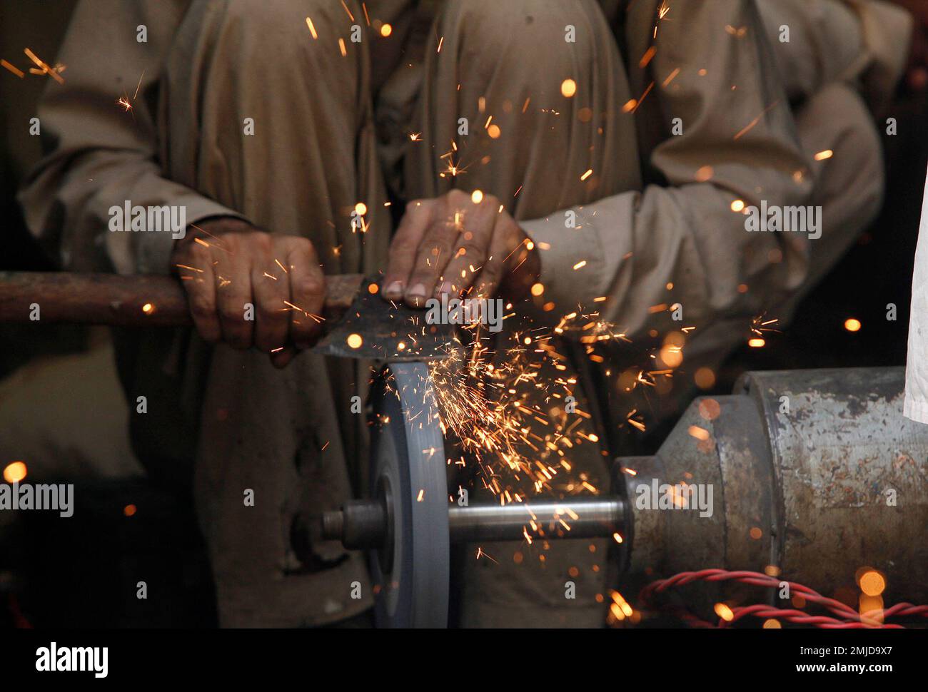 A Pakistani vendor sharpen axe for a customer, which will use to animal ...