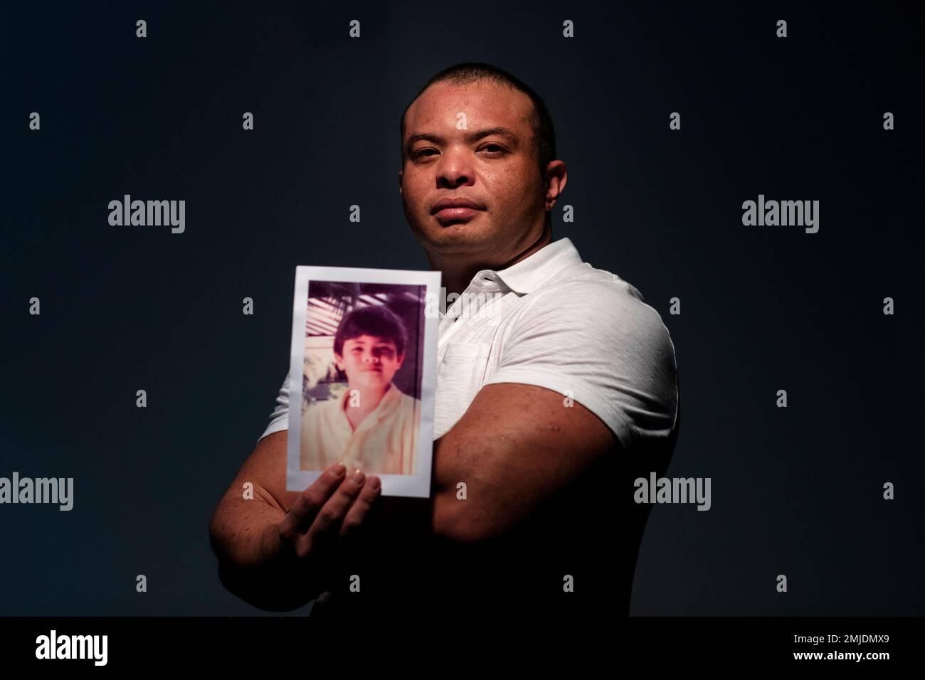 Troy Torres, 38, holds a photo of himself when he was about 12 years ...