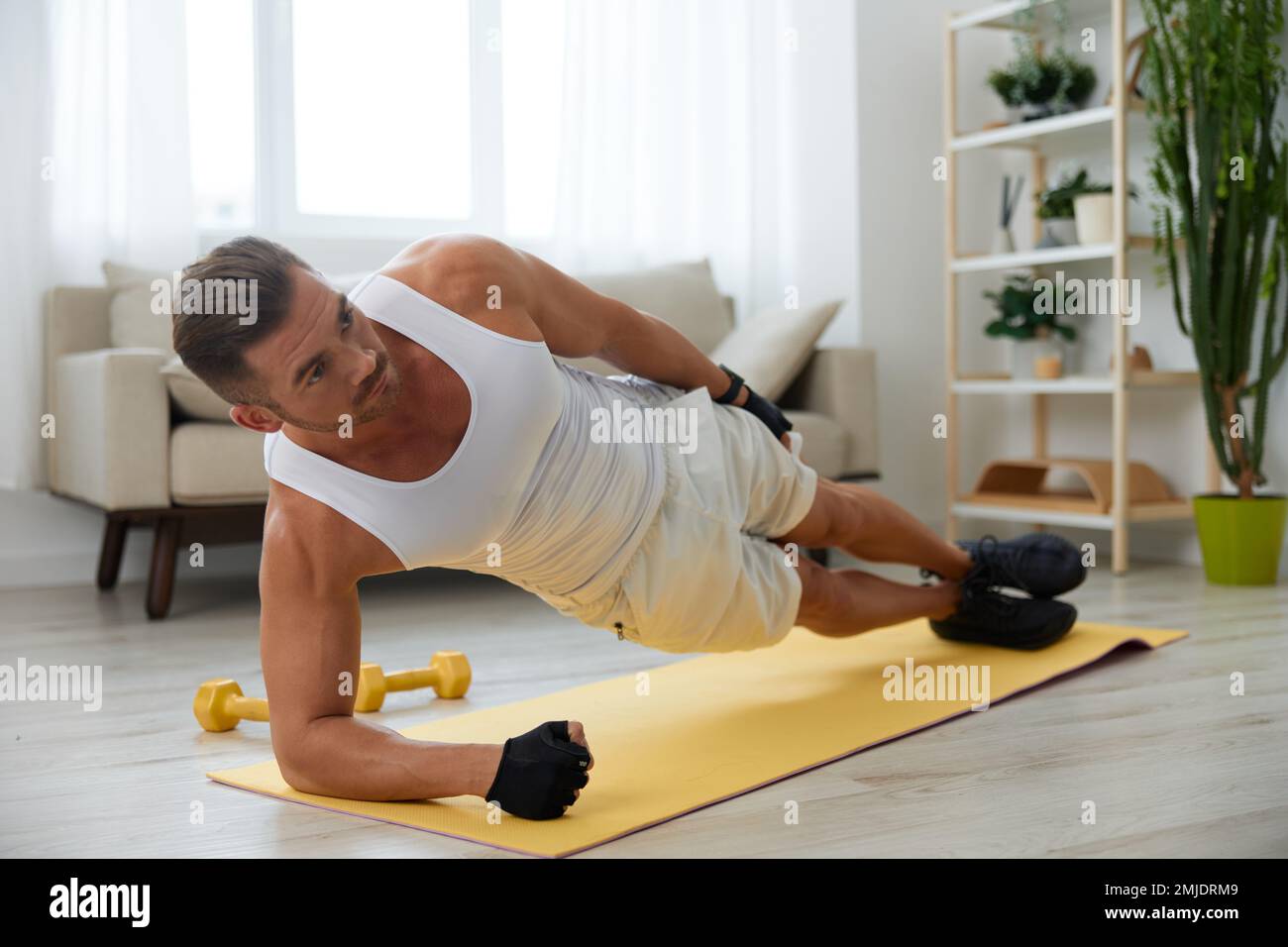 Man sports home training on the floor on a mat with dumbbells ...