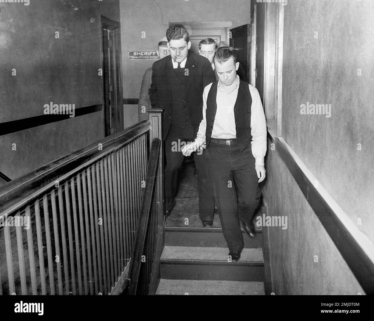 Outlaw John Dillinger is led from the jail to the courtroom by officers ...