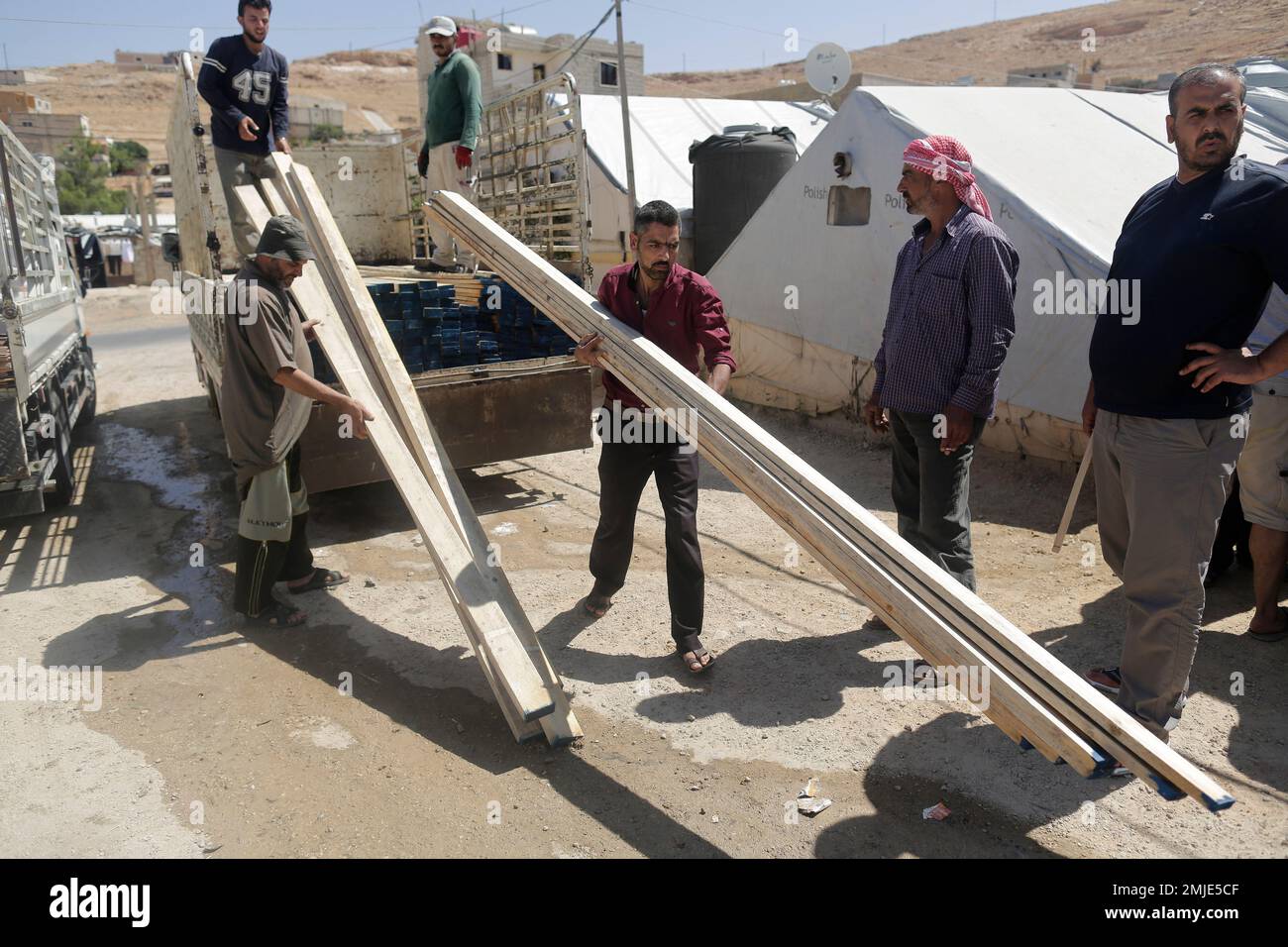 Syrian refugees carry wood beams and columns at a refugee camp in the ...