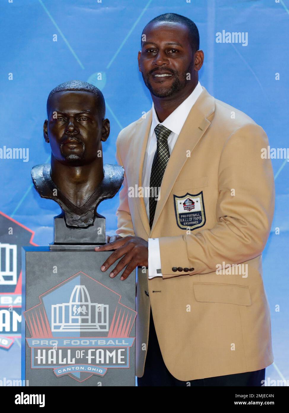 Former NFL player Ty Law poses with a bust of himself during the ...