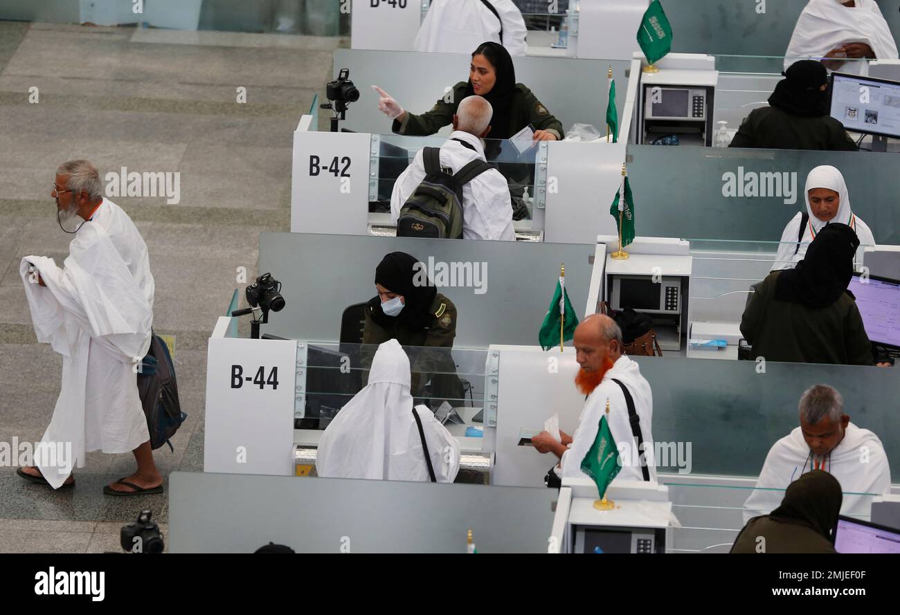 Pilgrims stamp their passports as they arrive at the Hajj Terminal at ...