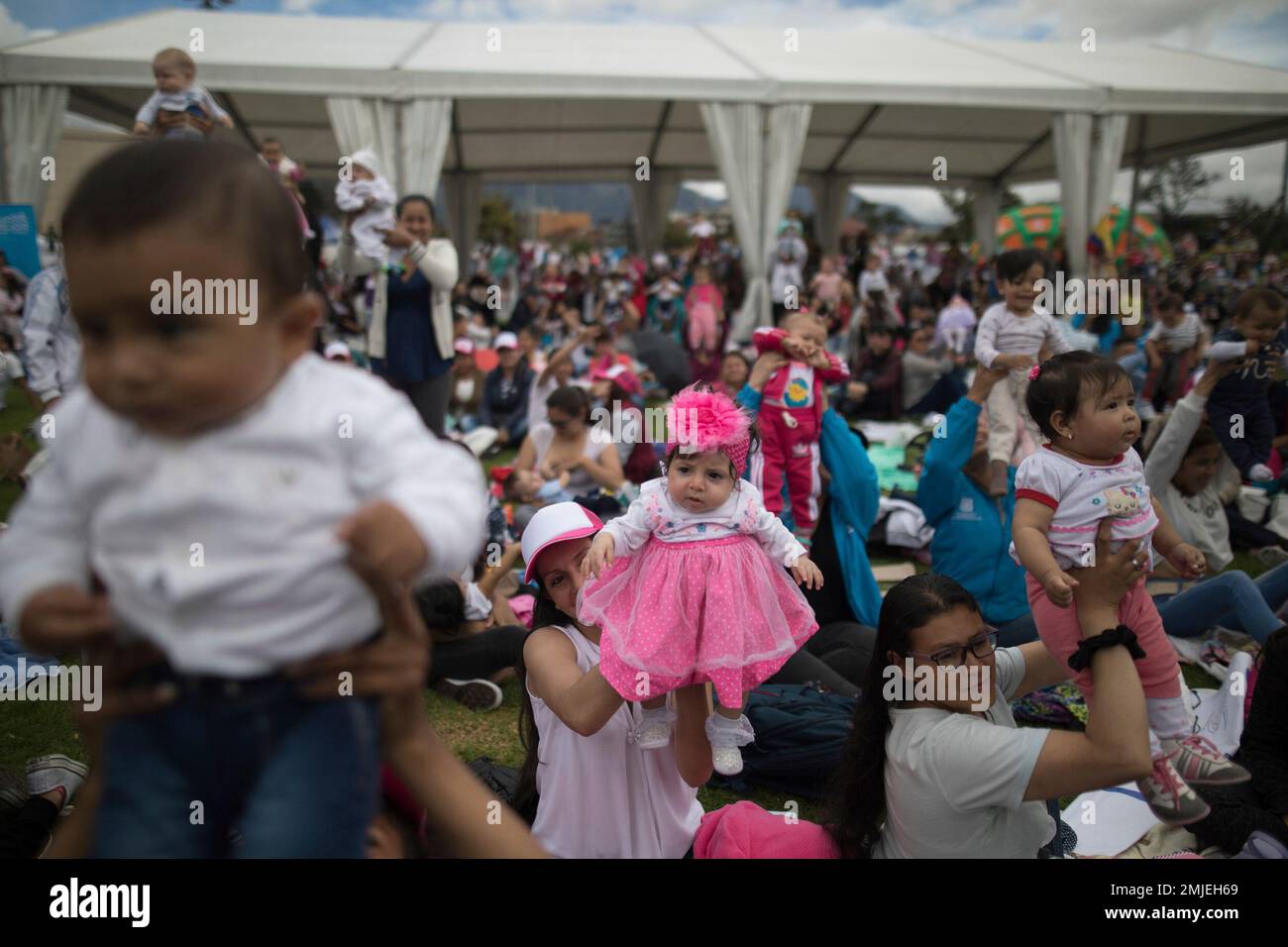 Women hold up their babies at a park where thousands of nursing mothers ...