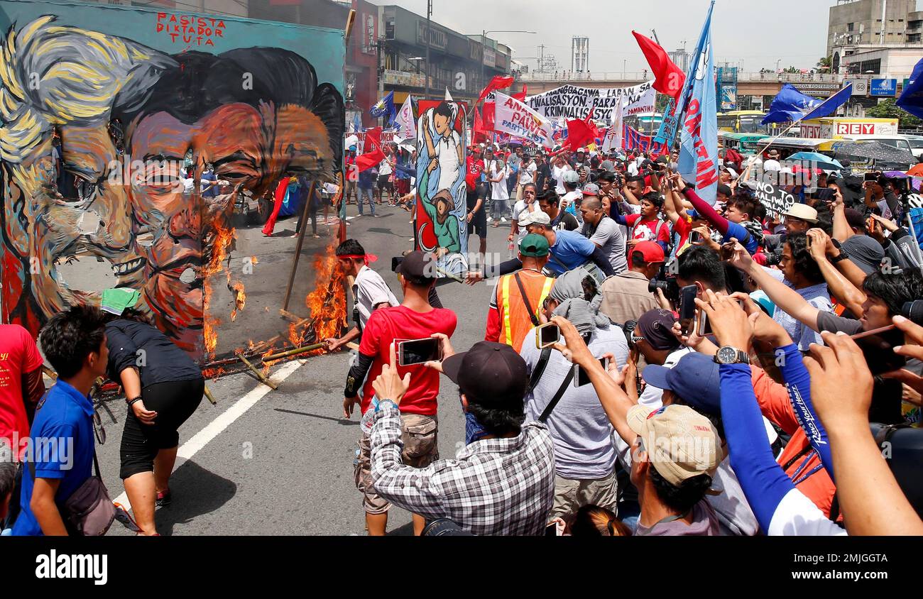 Protesters burn a giant mural of, from left, U.S. President Donald ...