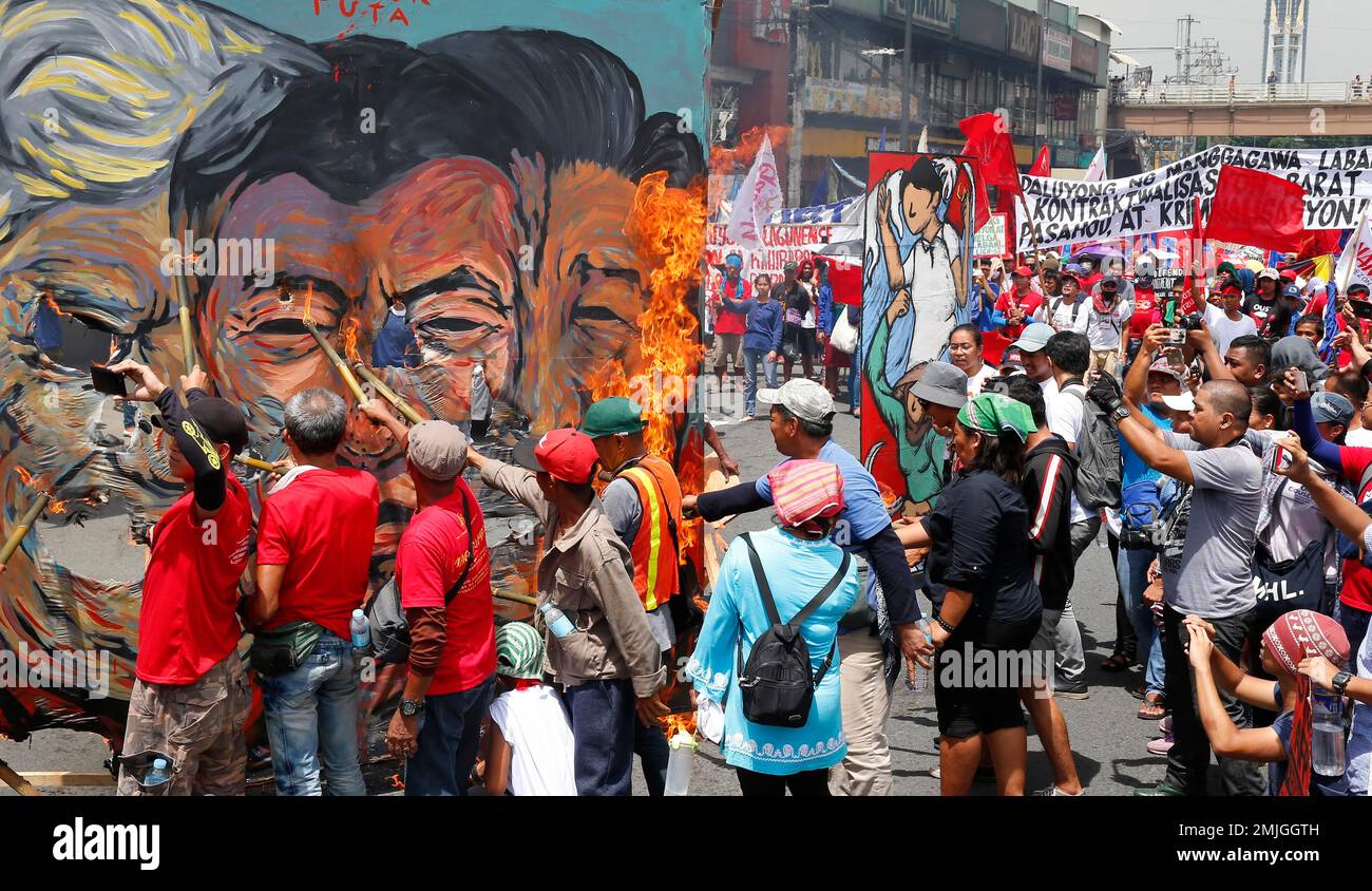 Protesters burn a giant mural of, from left, U.S. President Donald ...