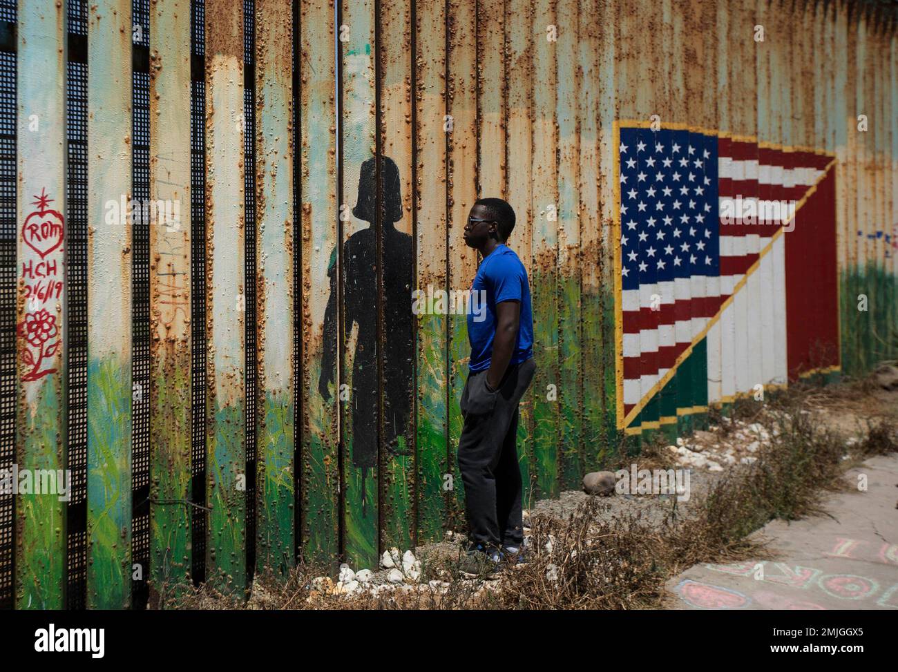 A man looks through the U.S. - Mexico border fence after a binational ...