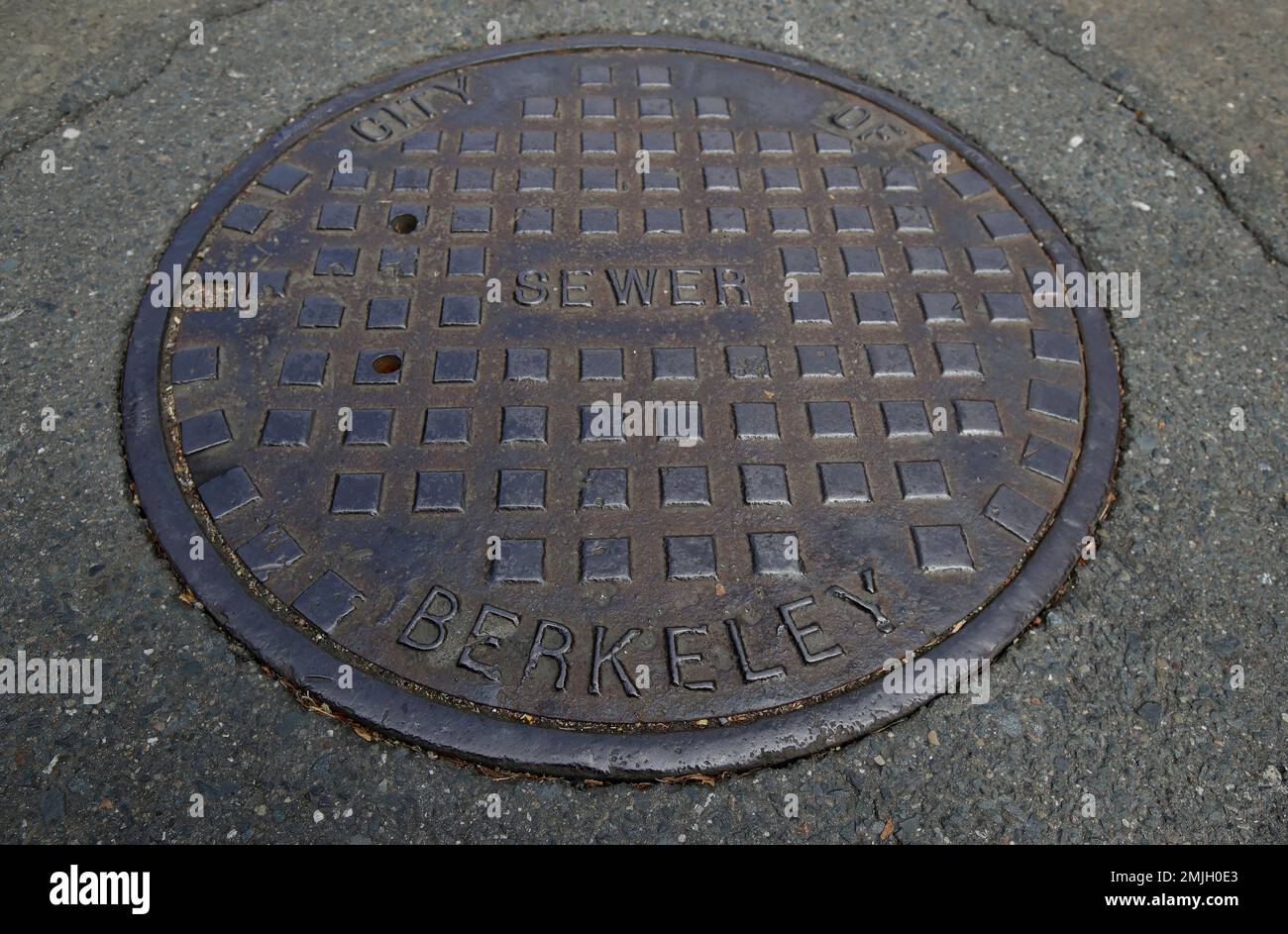 A manhole cover for a sewer is shown in an intersection in Berkeley ...