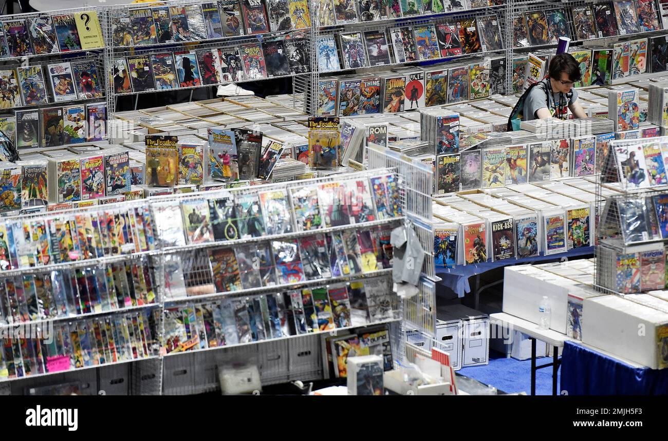 A lone Comic-Con attendee searches through stacks of comic books on the ...