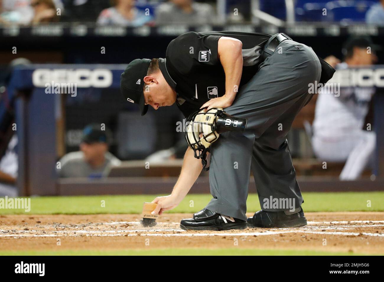 Home plate umpire D.J. Reyburn brushes off home plate during the third ...