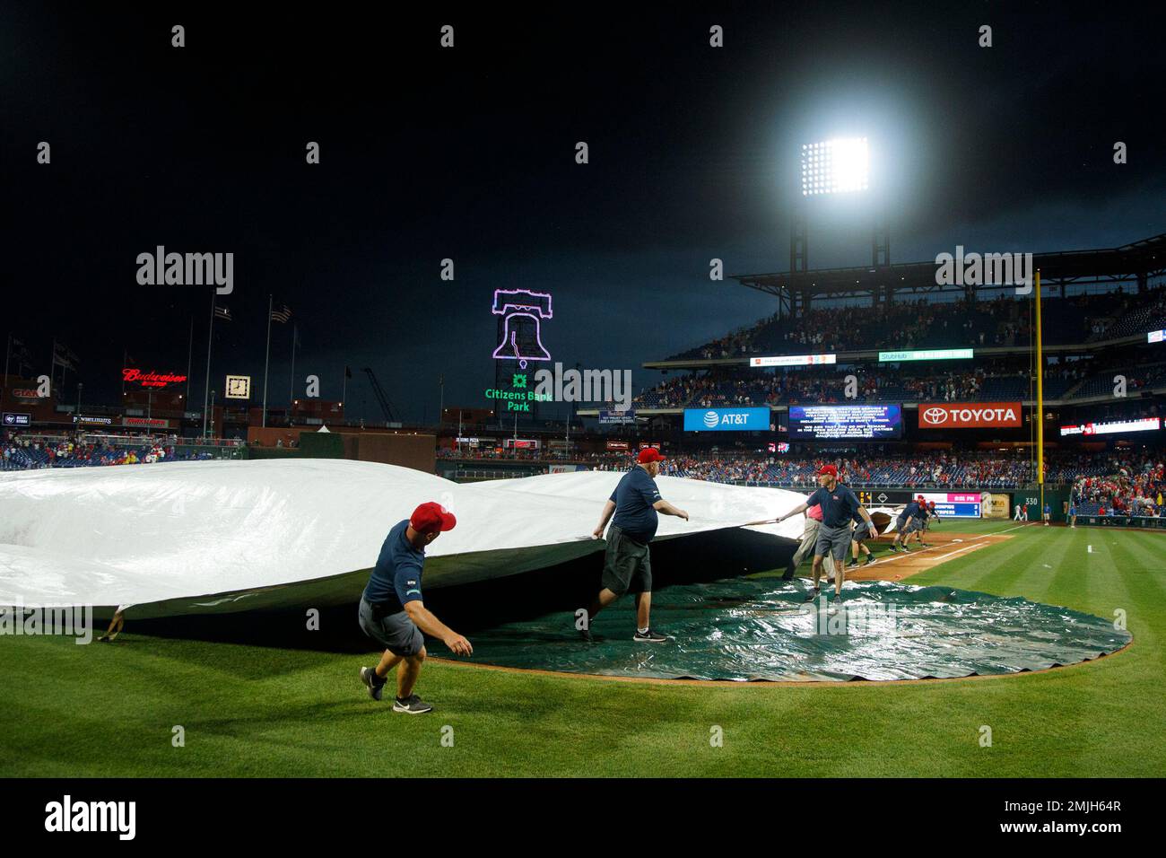 Workers cover the infield as inclement weather delays a baseball game ...