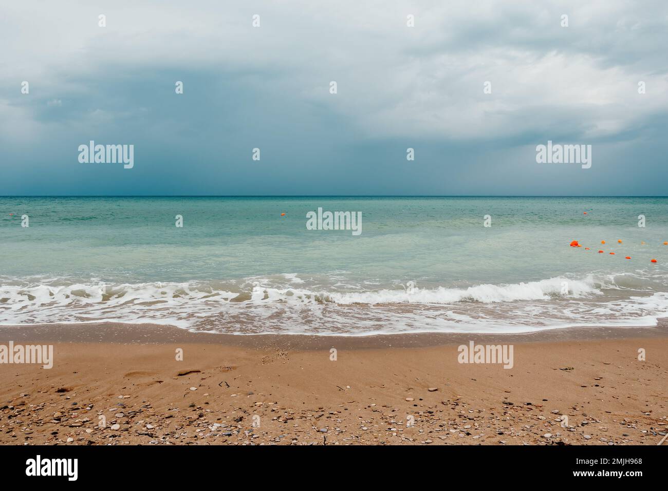 Overcast sky on rainy day with foamy waves rolling towards golden sand ...