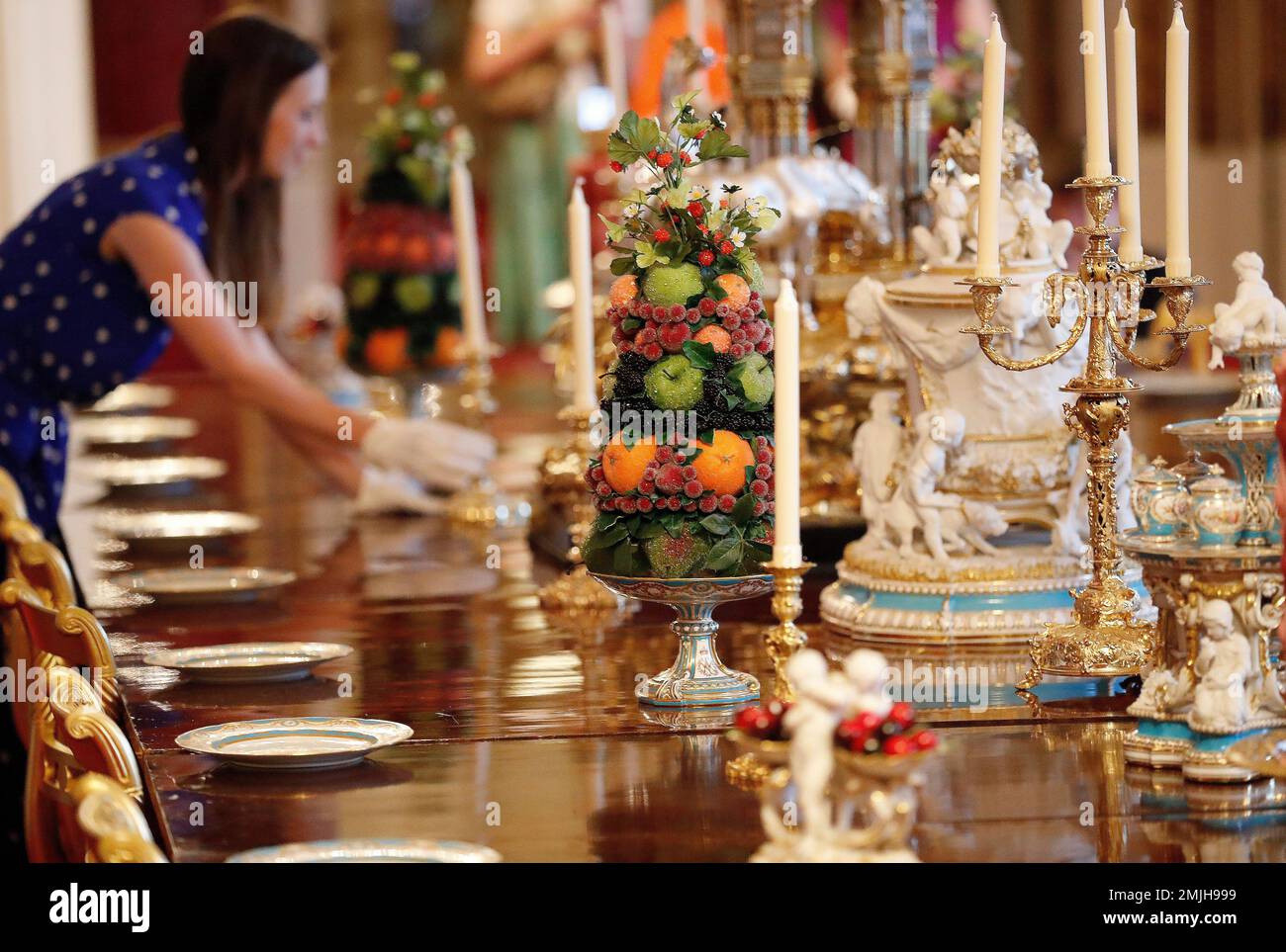 A member of the Buckingham Palace staff arranges the dining table, a ...