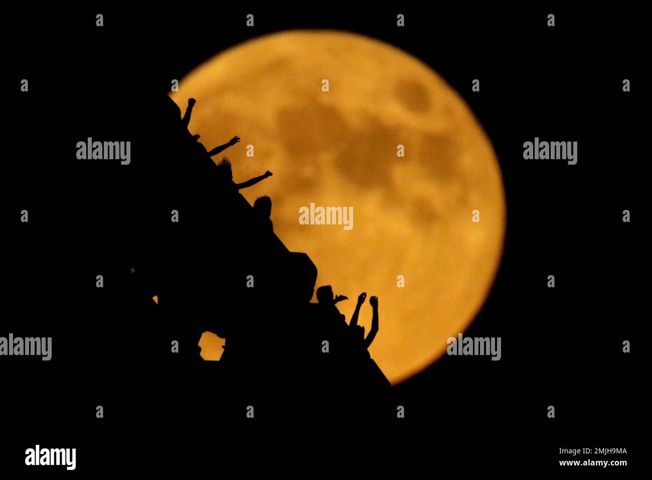 The full moon rises, silhouetting roller coaster riders at the Worlds ...