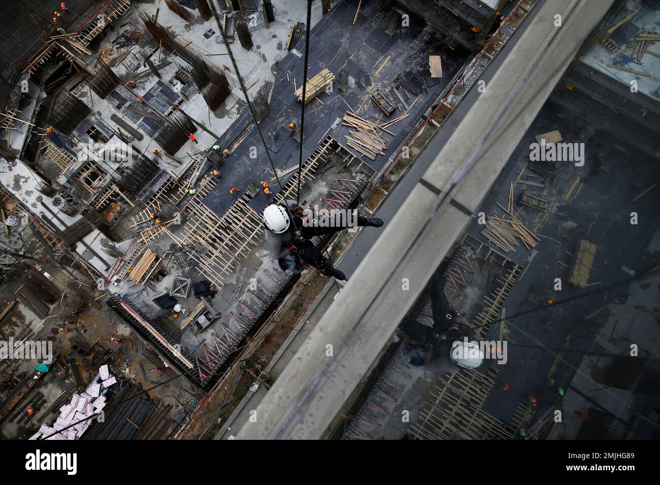 A window cleaner rappelling down the side of a high-rise building in ...