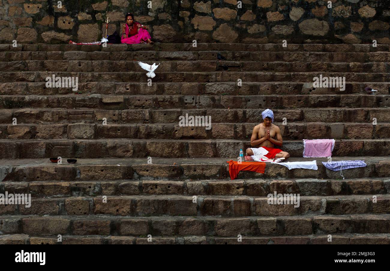 In this June 22, 2019 photo, devotees perform rituals sitting on steps ...