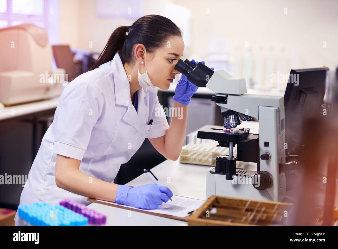 Always on the lookout for a cure. a young scientist taking notes while ...