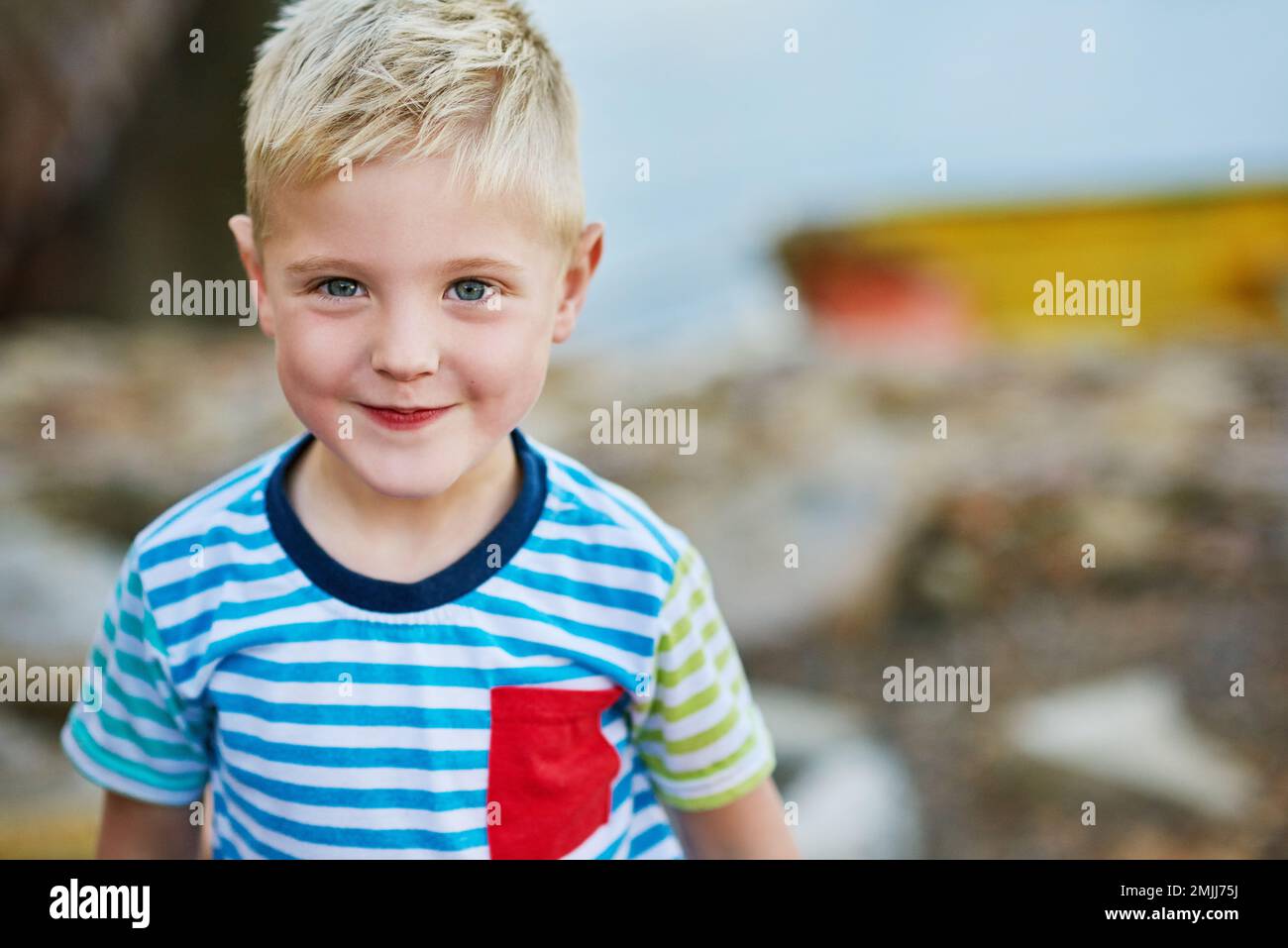 Hes a natural cutie. Portrait of a happy little boy posing outside on ...