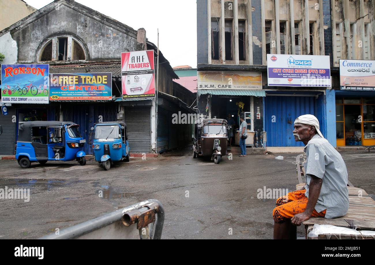 A Sri Lankan daily wage laborer sits awaiting work at a market place in ...