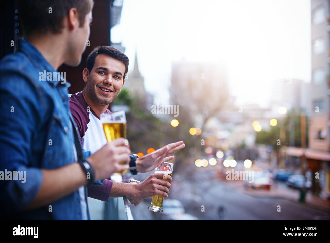 Unwinding for the weekend. two guys drinking beer while standing on the balcony at a party Stock ...