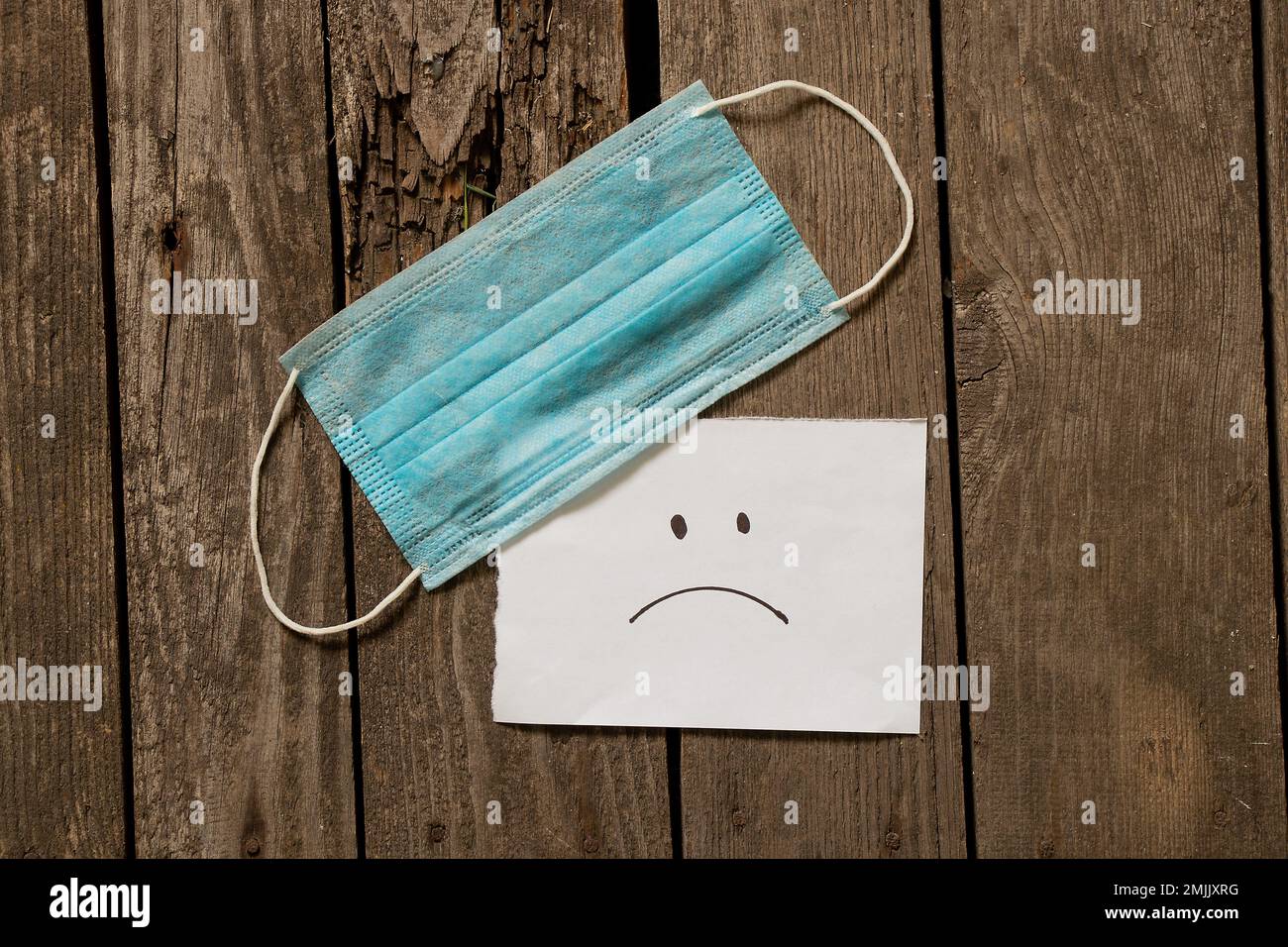 medical mask sad emoticon painted on white paper on a table Stock Photo ...