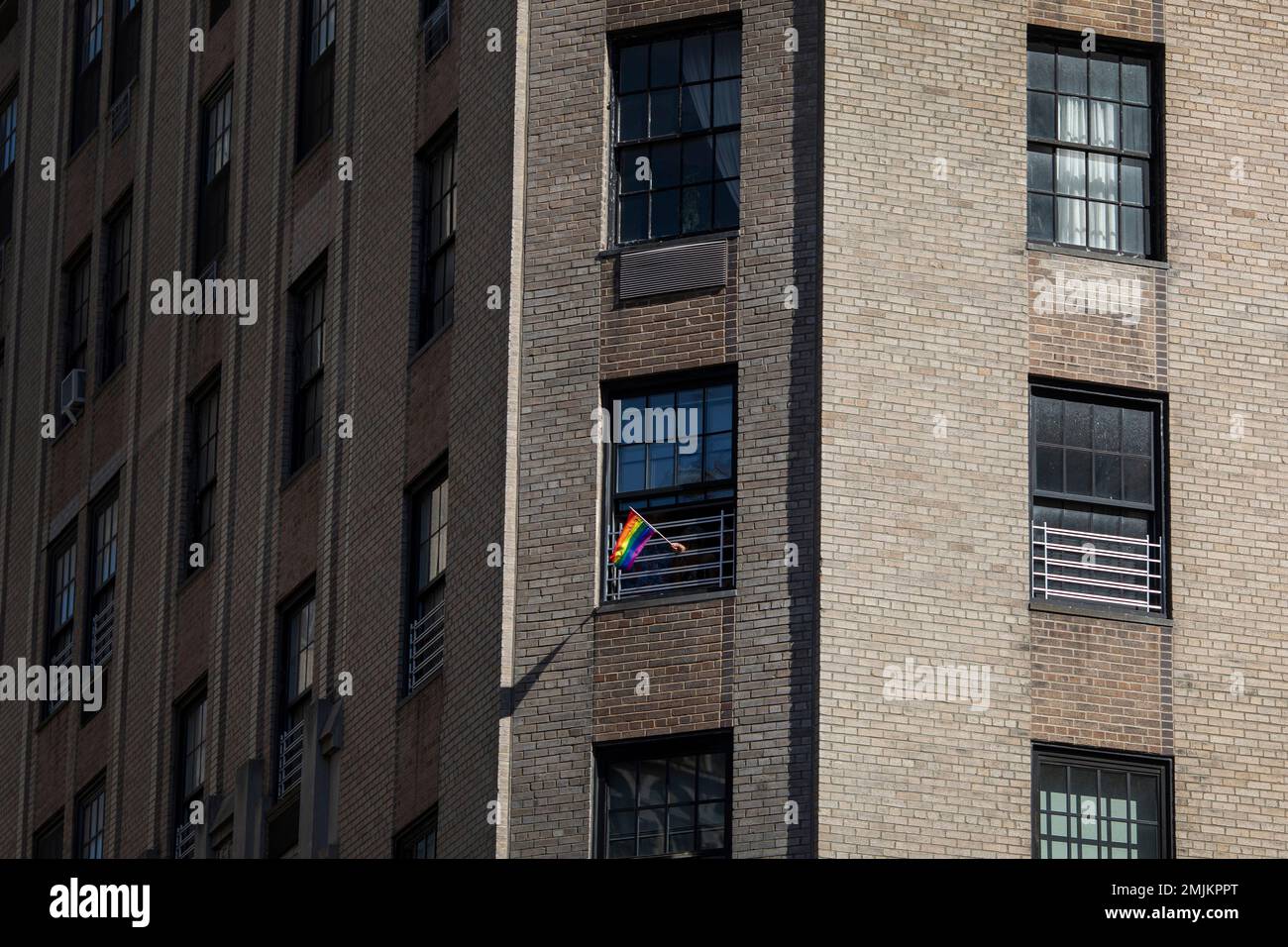 A rainbow flag is waved through window grills in an apartment ...