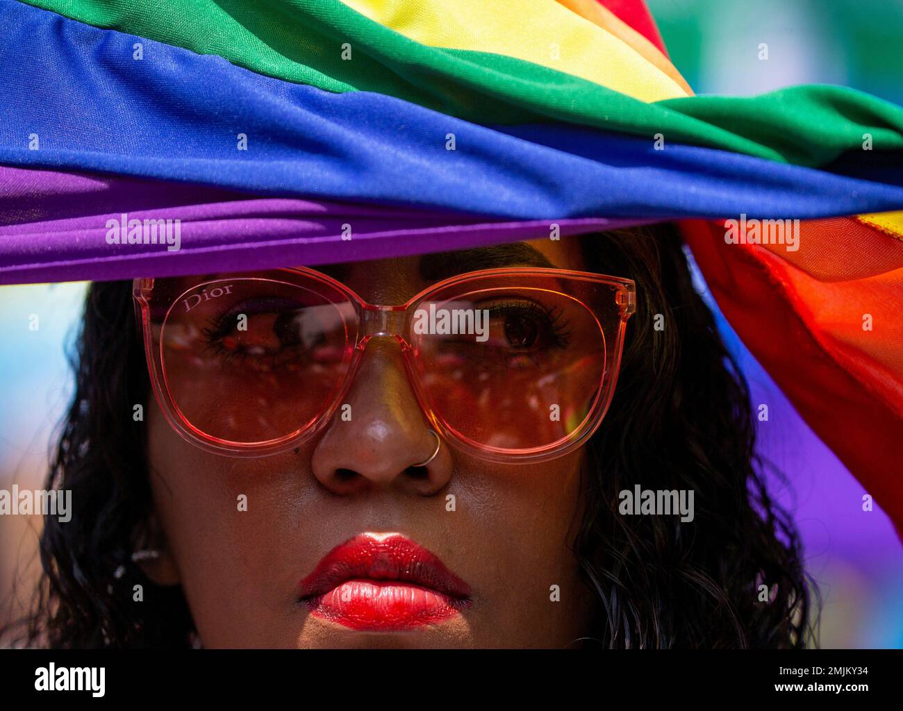 A reveler covers himself from the sun with a rainbow flag during the ...