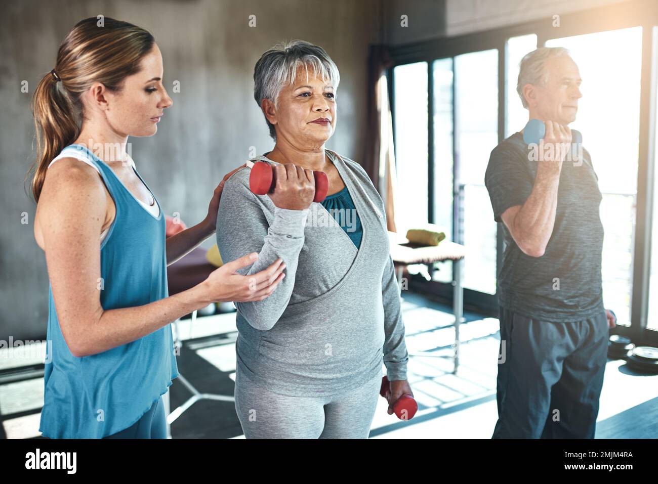 Time to get up and get moving. a senior man and woman using weights ...