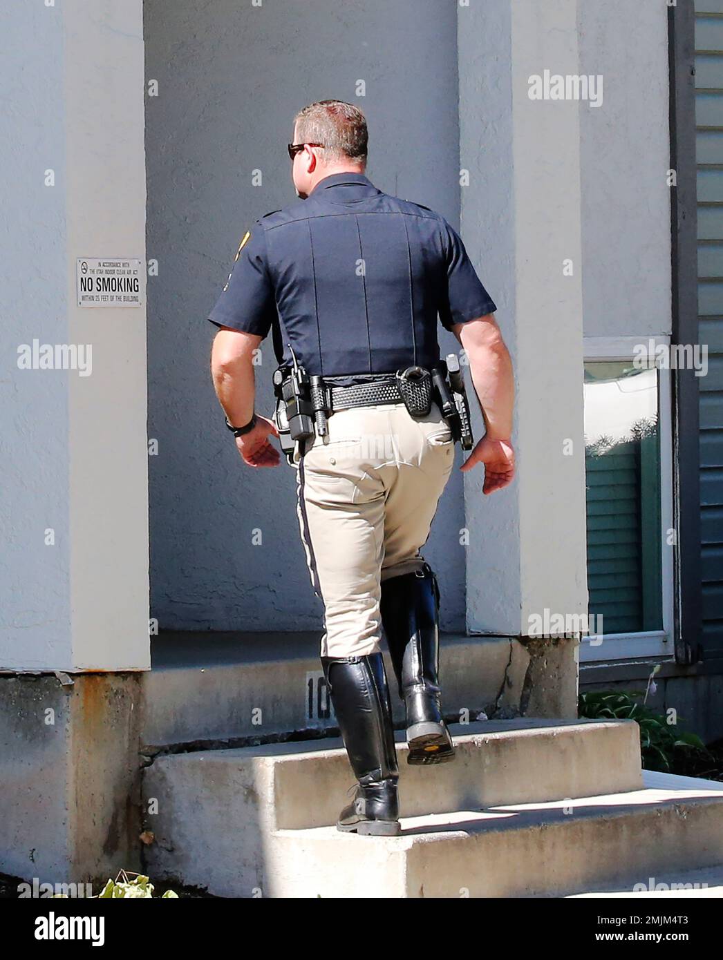 A police officer walks into a building where a man was taken into ...