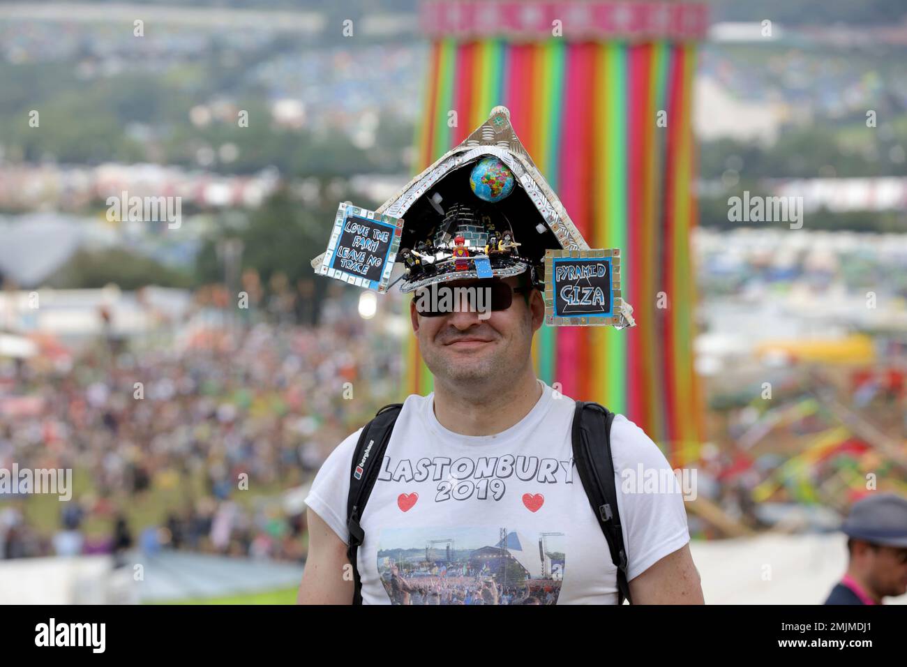 A reveller wears a hat shaped like the main Pyramid Stage at the ...