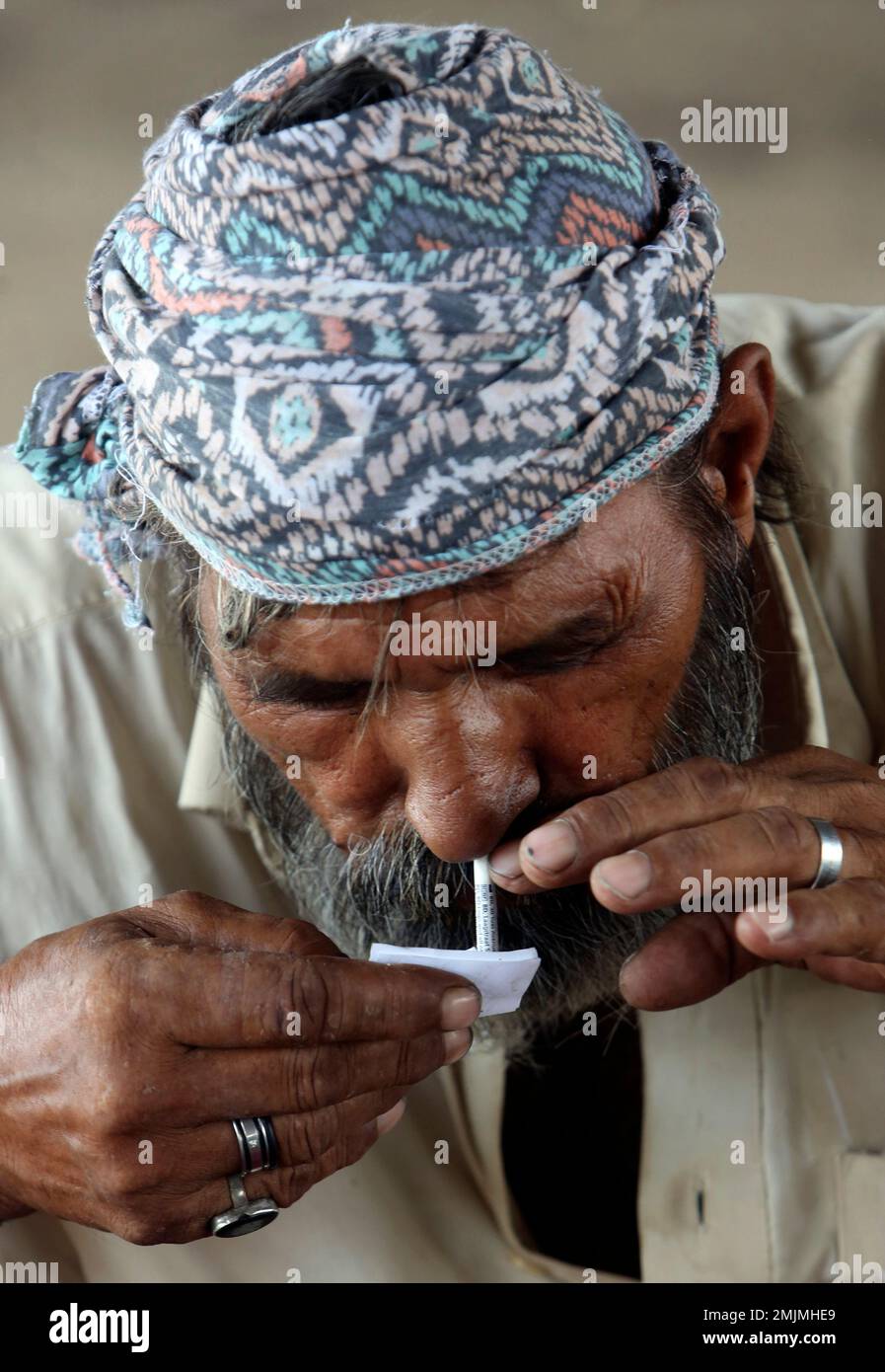 A Pakistani drug addict sniffs heroin at a roadside in Karachi ...