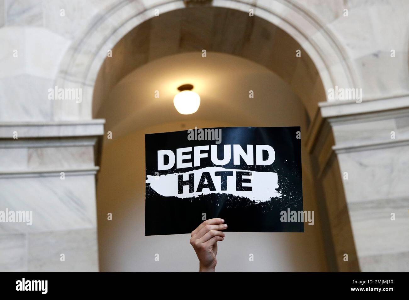 A protester holds up a sign as she gathers with others to demand the ...