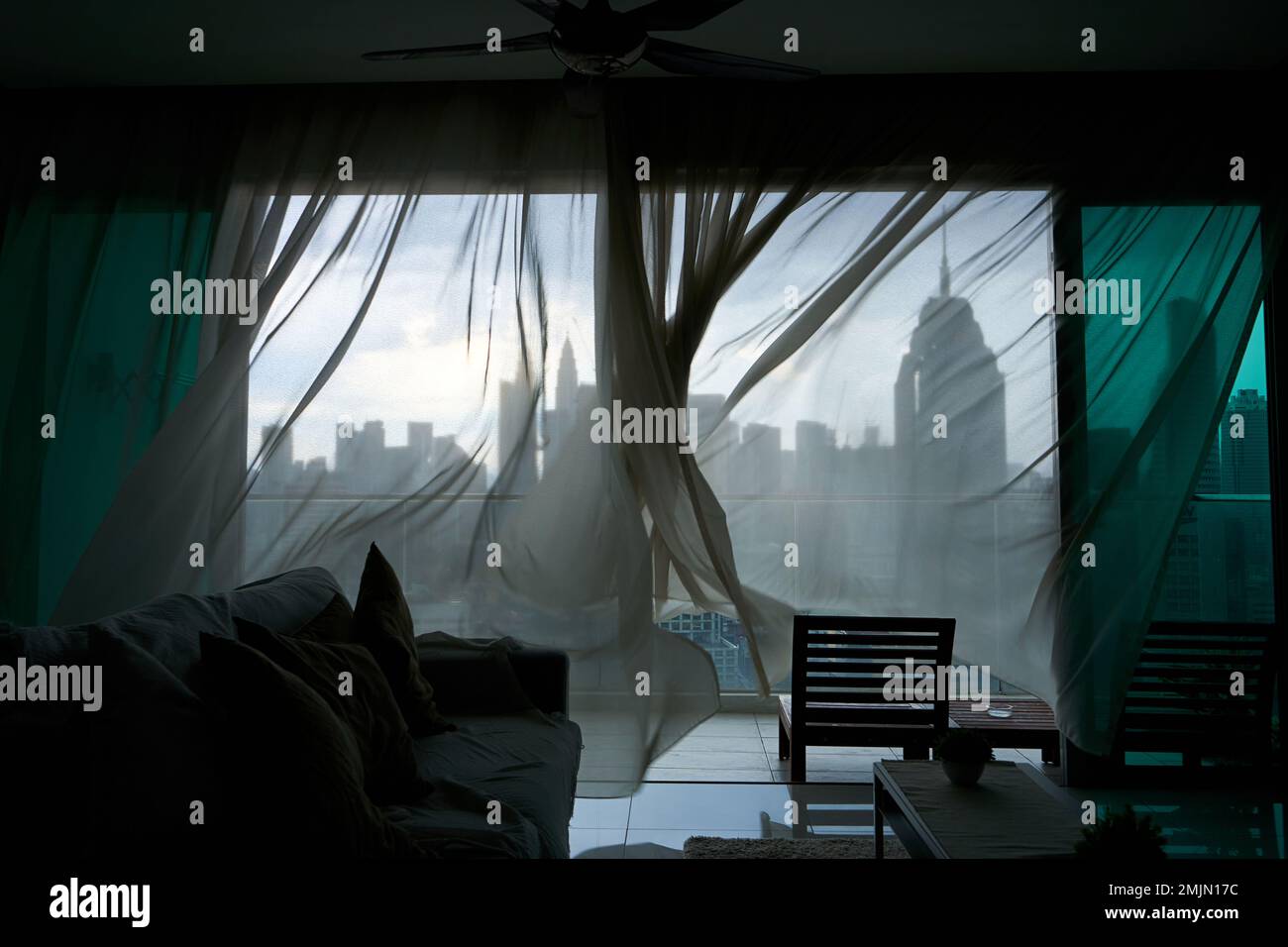 The wind rustles the curtain of the panoramic window with a cityscape ...